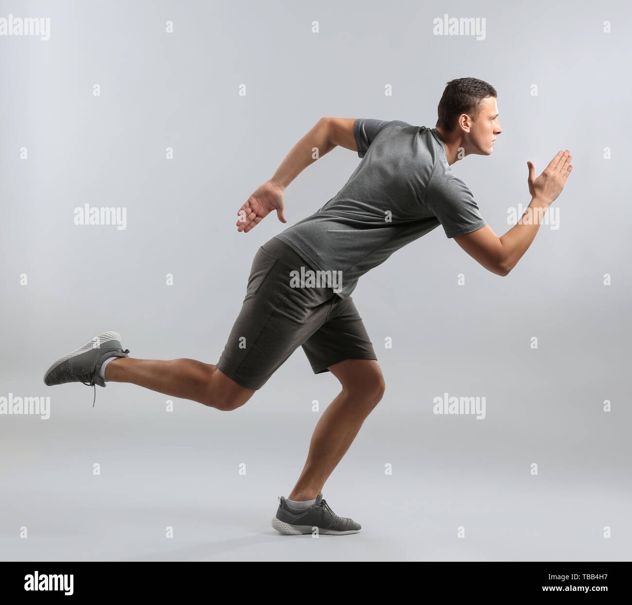 Sporty young man running against grey background Stock Photo - Alamy