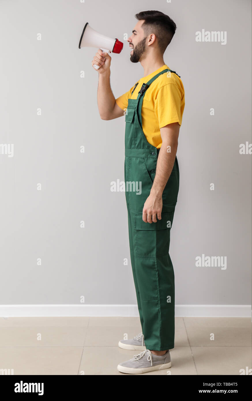 Handsome worker with megaphone near light wall Stock Photo - Alamy