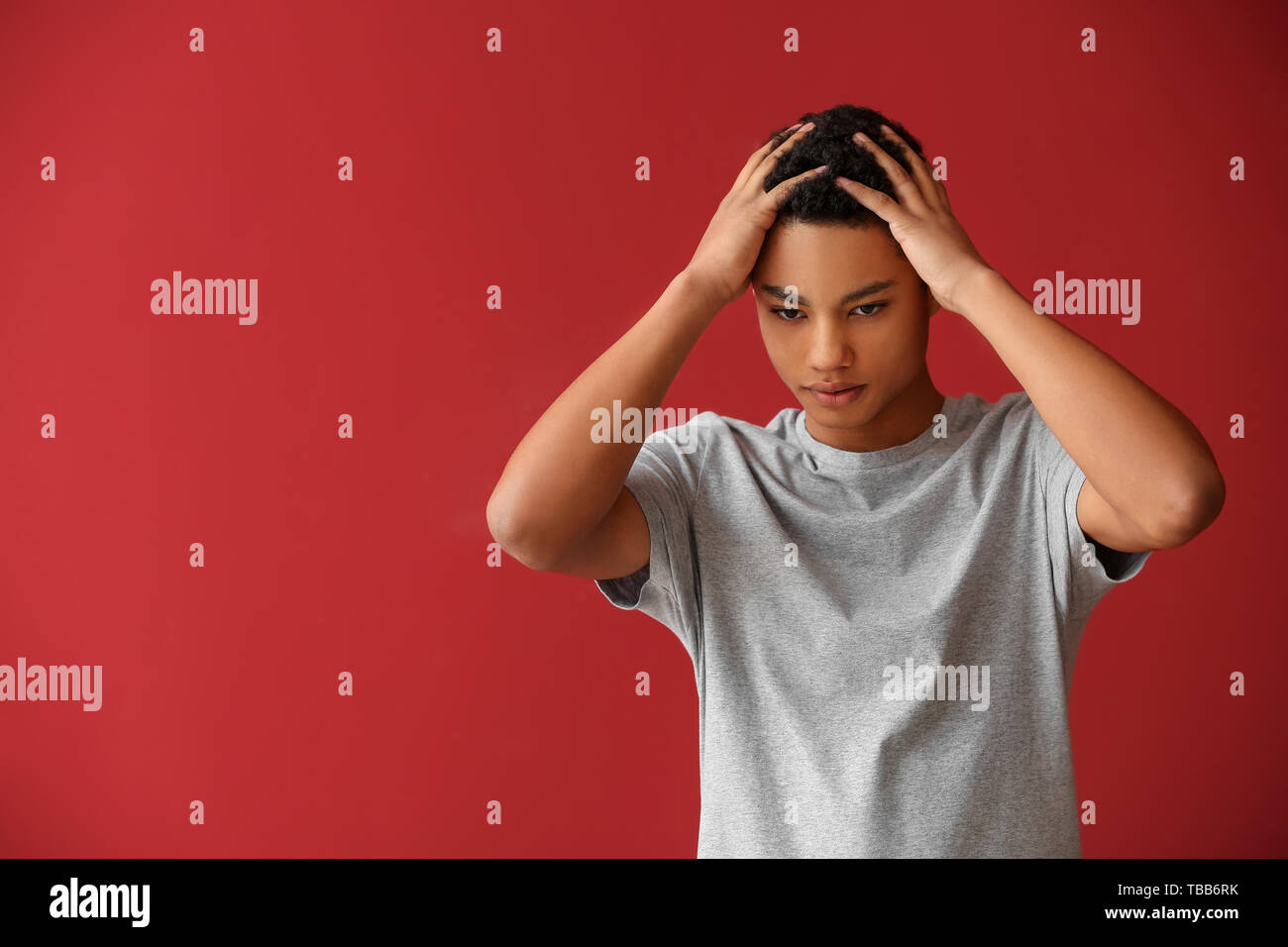 African-American boy after failing school test on color background ...