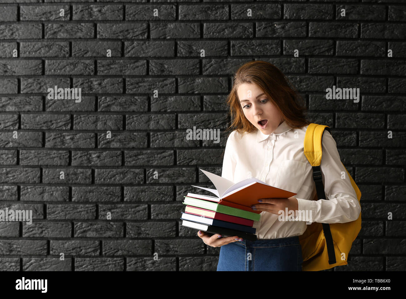 Schoolgirl with books on dark background Stock Photo - Alamy