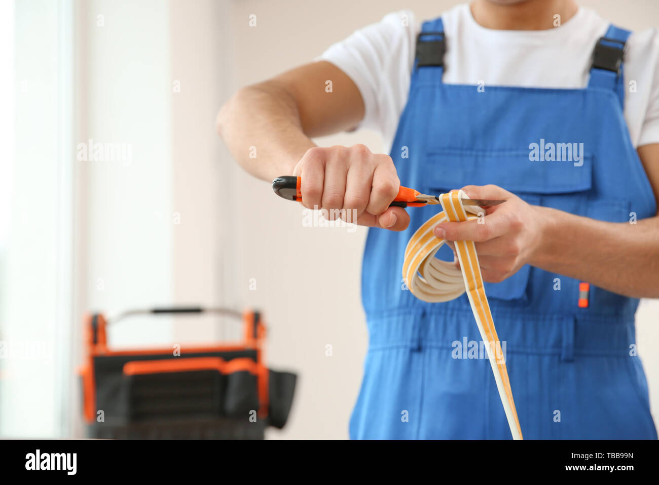 Young worker cutting seal for installation of window Stock Photo - Alamy