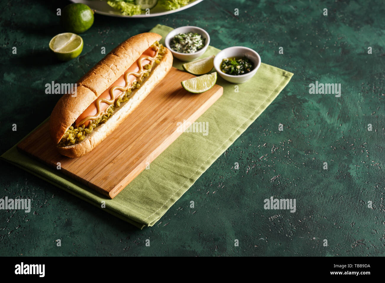 Wooden board with tasty hot dog on color table Stock Photo - Alamy
