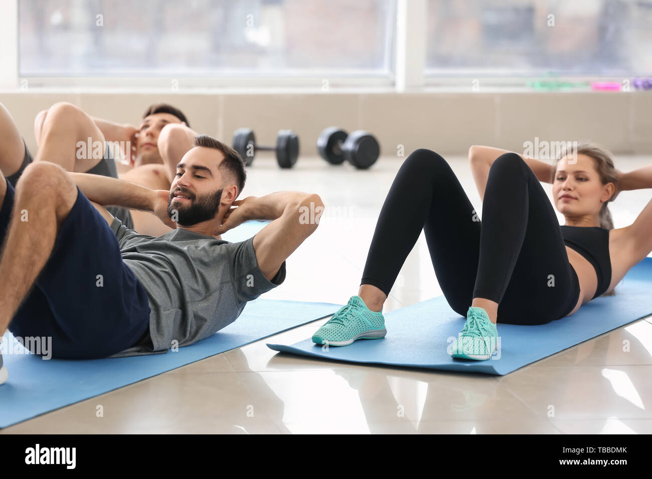Sporty young people doing crunches in gym Stock Photo - Alamy