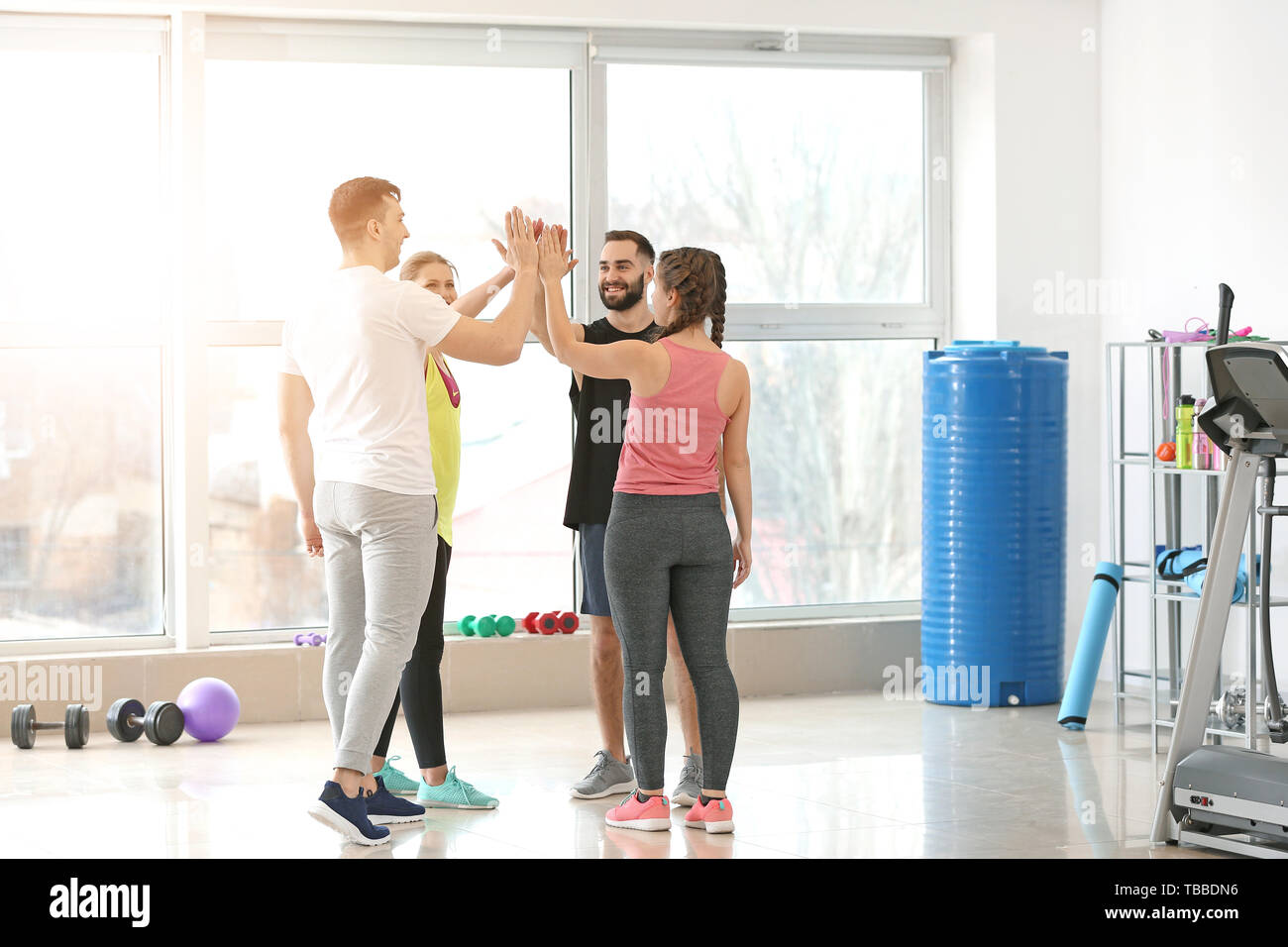 Sporty young people putting hands together in gym Stock Photo - Alamy