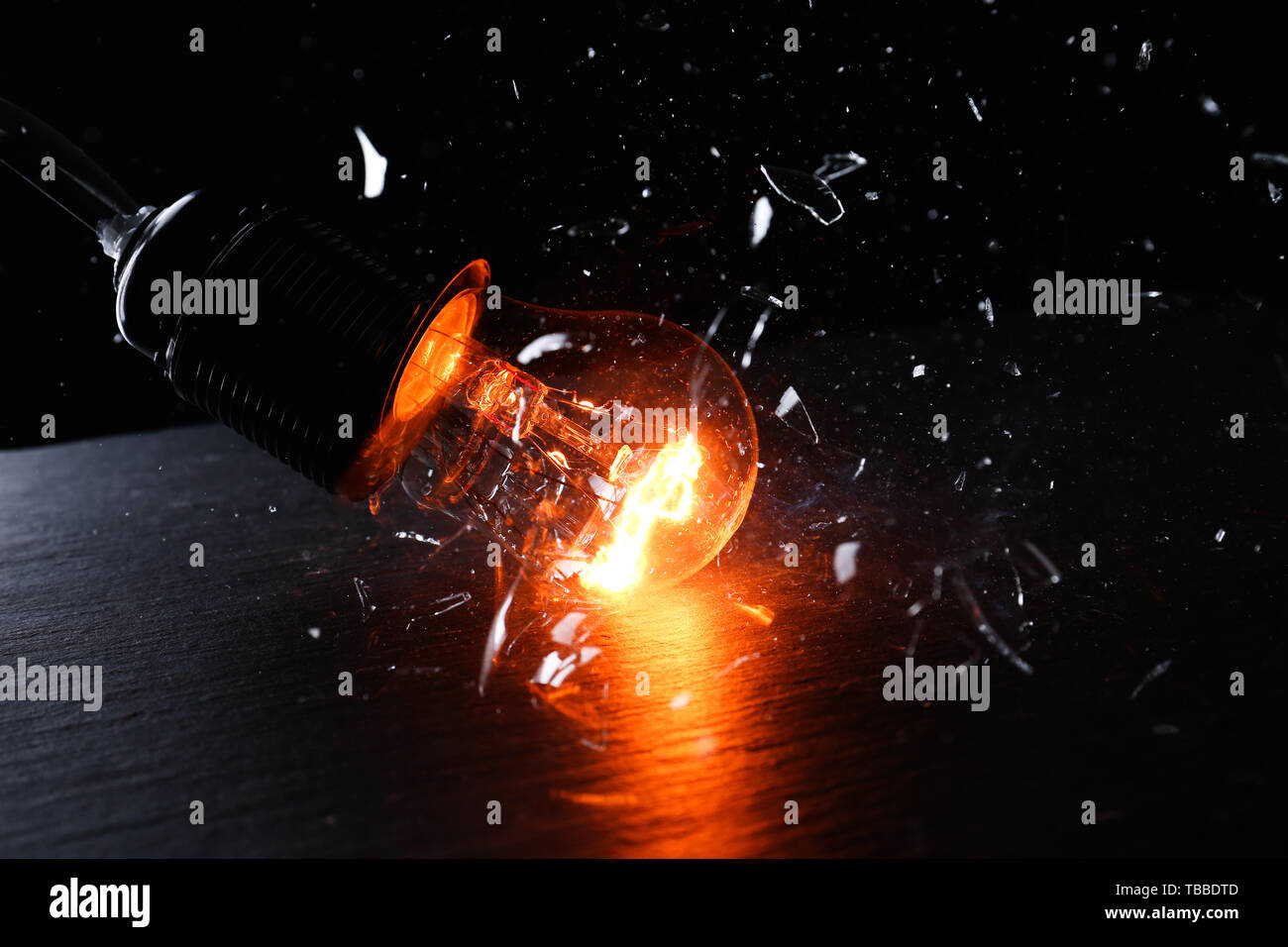 Breaking of light bulb on dark background Stock Photo - Alamy