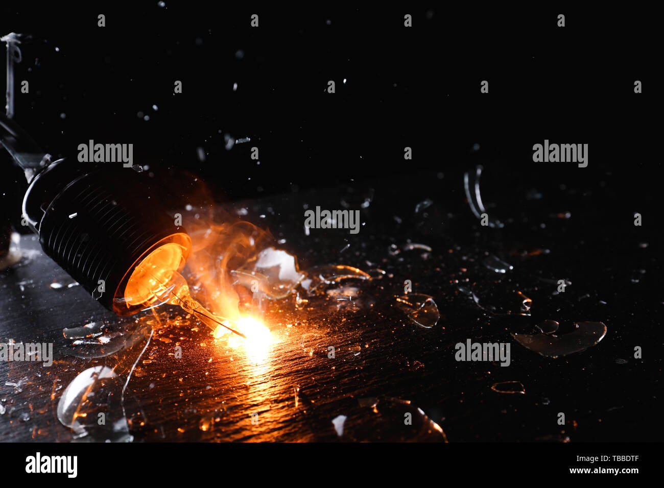 Breaking of light bulb on dark background Stock Photo - Alamy