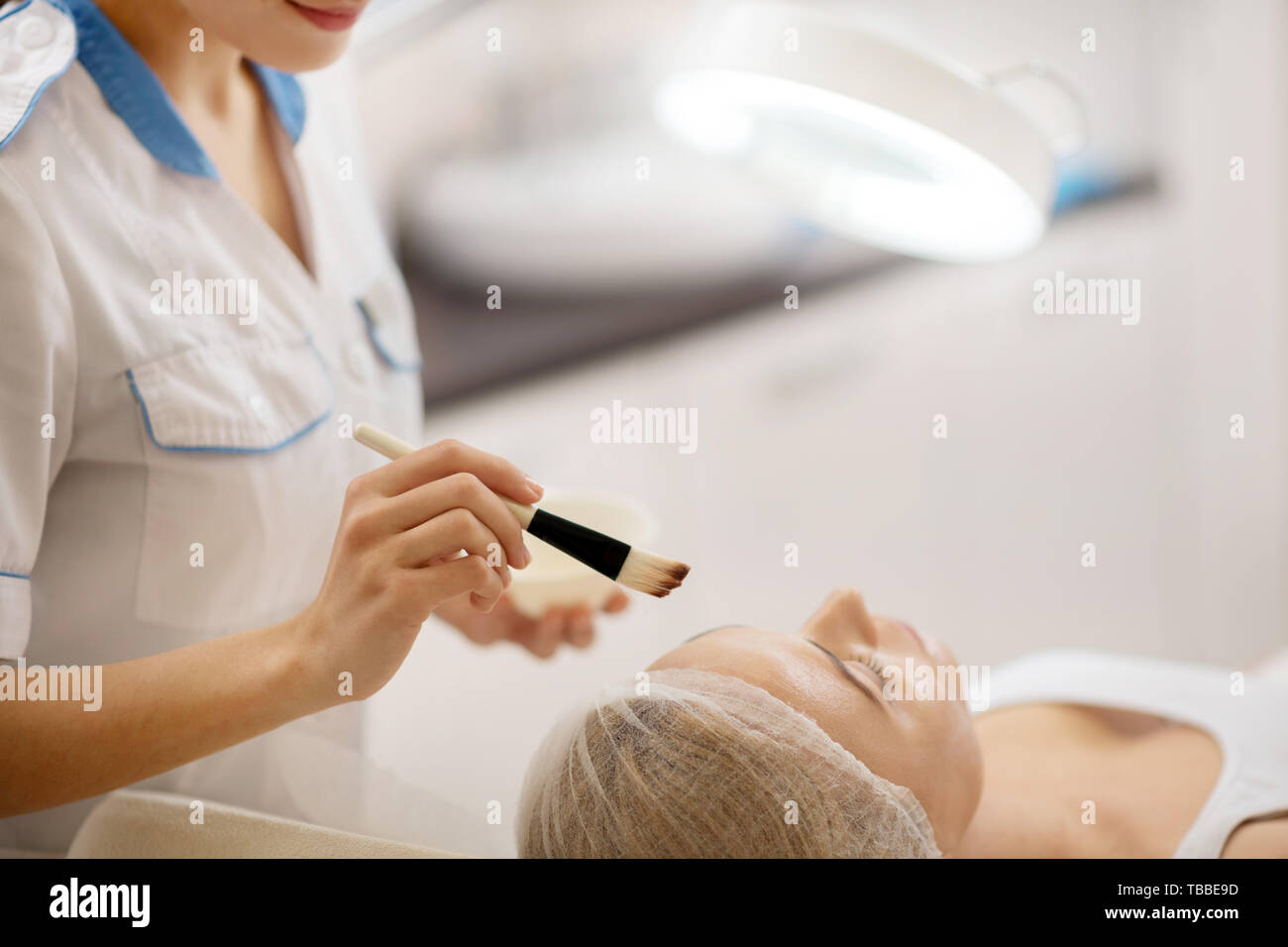 In white uniform. Dermatologist in white uniform holding brush with ...