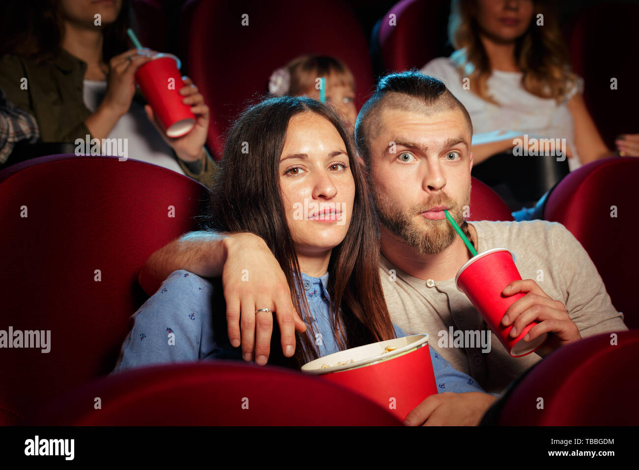 friends sitting in cinema watch film eating popcorn and drinking water ...