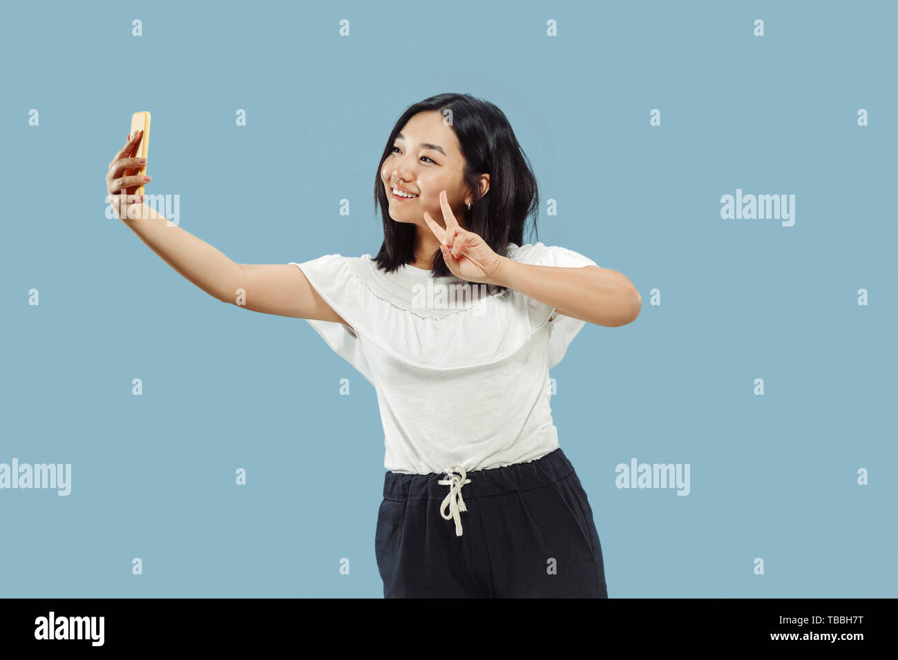 Korean young woman's half-length portrait on blue studio background ...