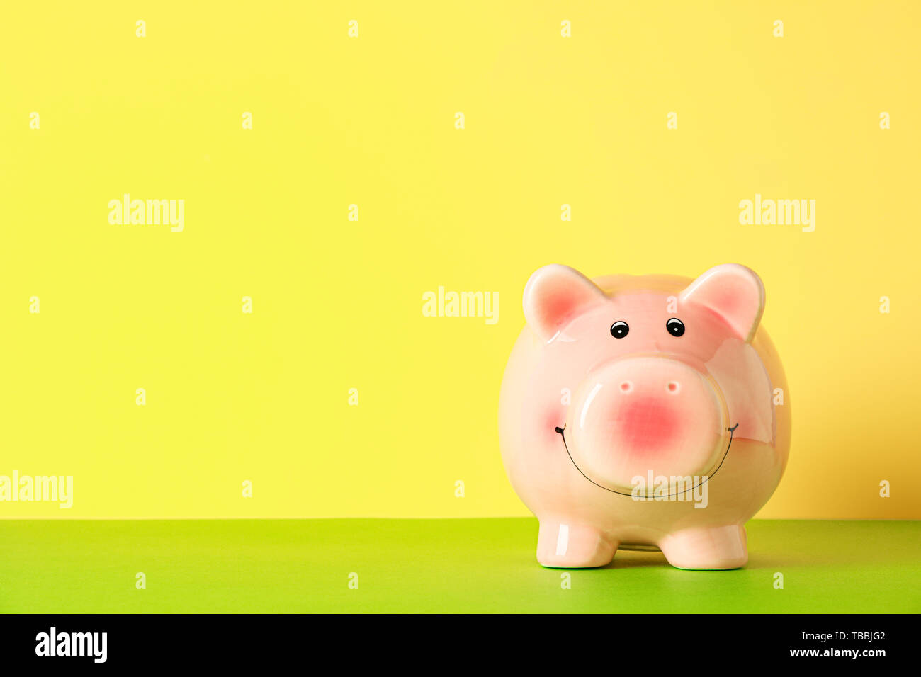 Happy piggy bank on color table against yellow background, space for ...