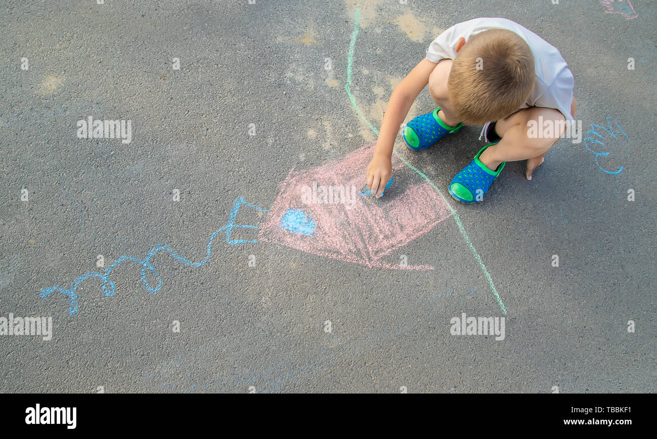 child draws a house in chalk on the pavement. Selective focus. nature ...