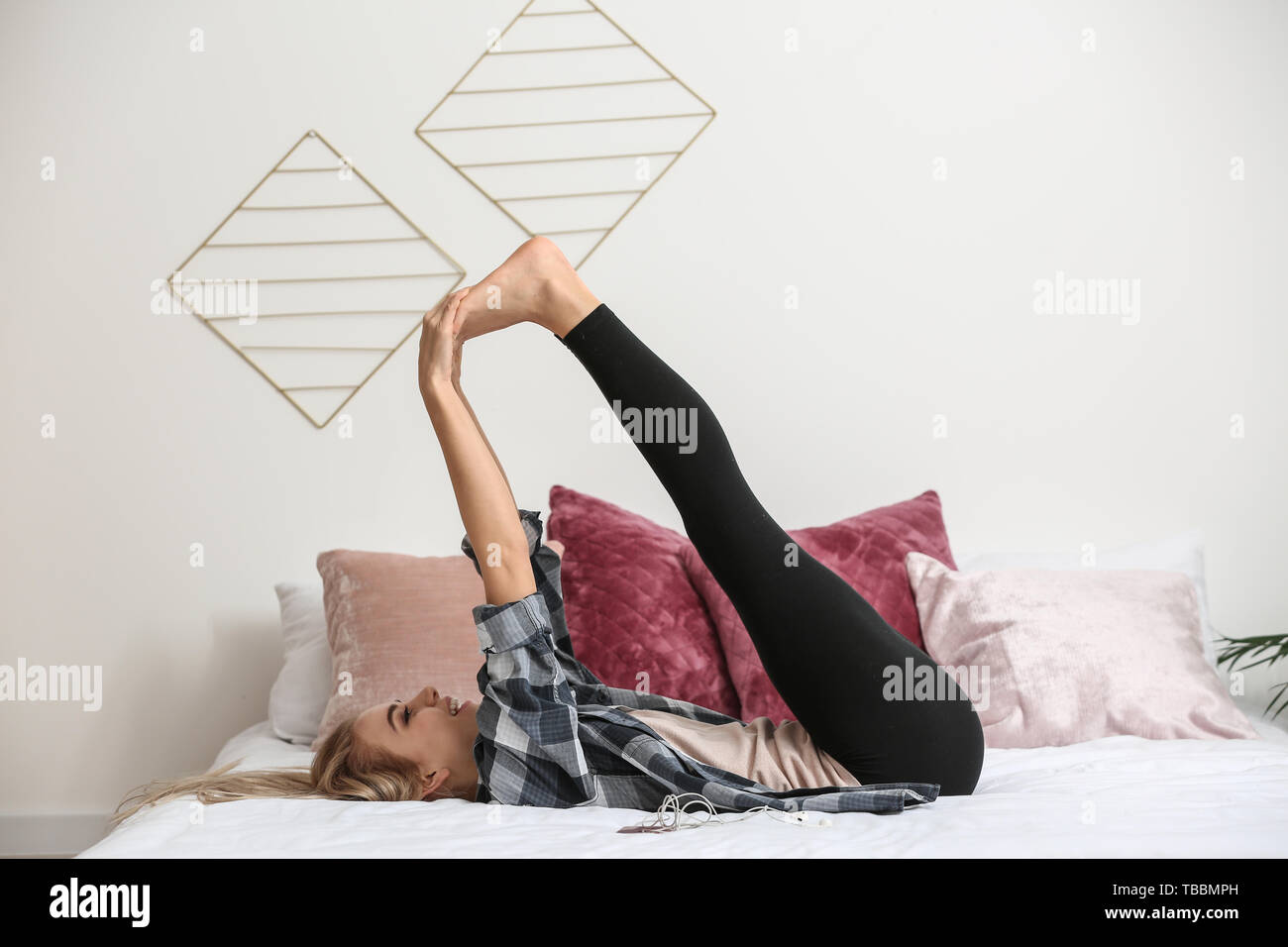 Sporty young woman stretching on bed Stock Photo - Alamy