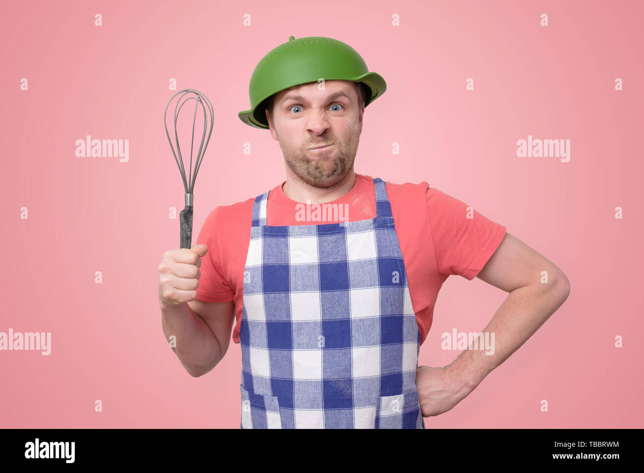 crazy man in an apron with a colander on his head Stock Photo - Alamy