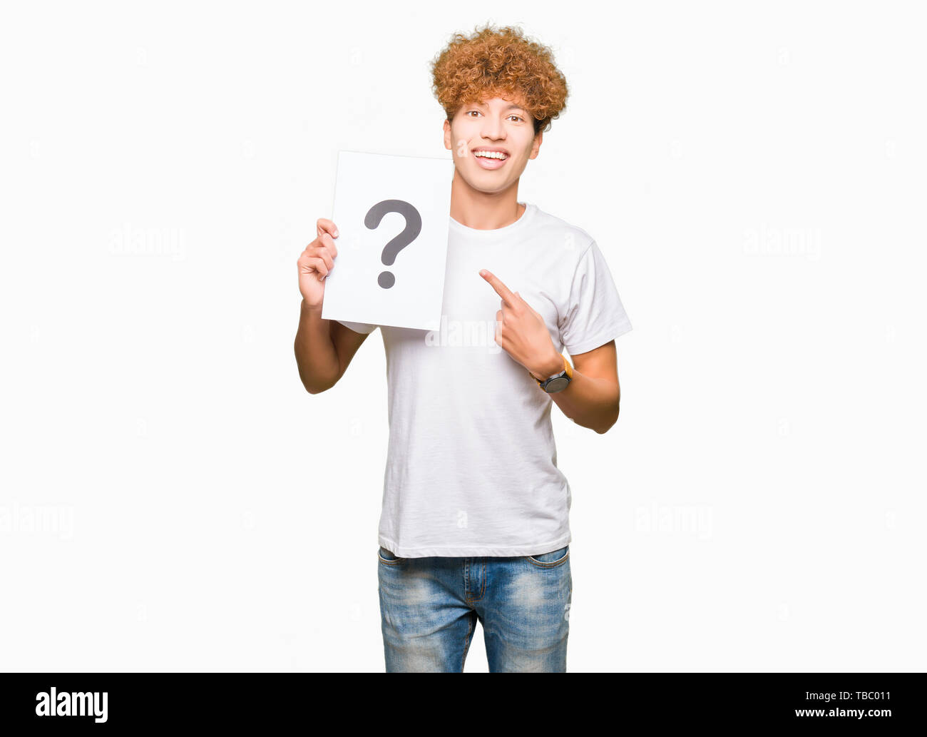 Young handsome man holding paper with question mark very happy pointing ...