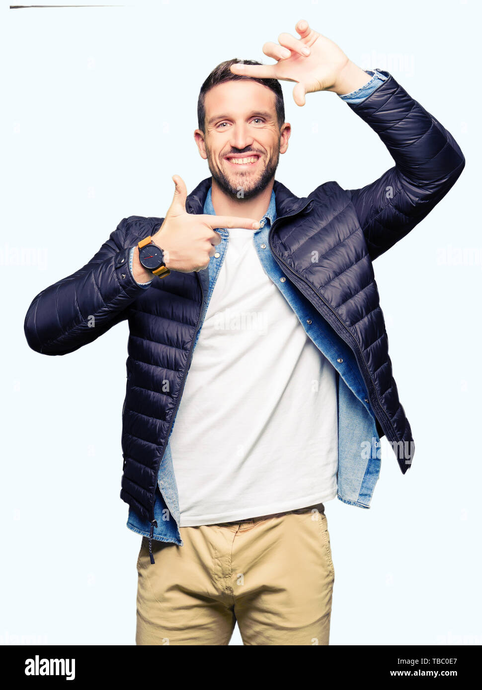 Handsome man wearing winter coat smiling making frame with hands and ...