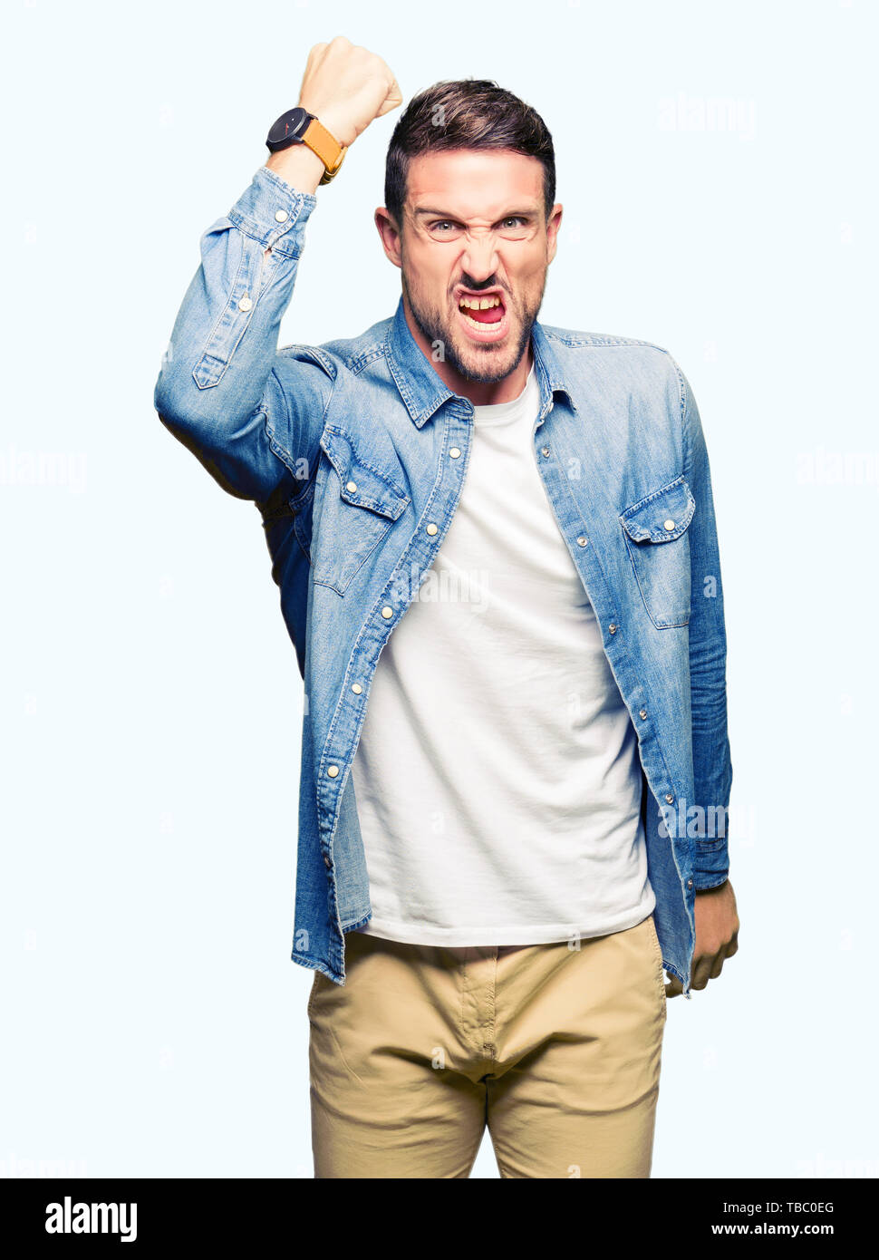 Handsome man with blue eyes and beard wearing denim jacket angry and ...