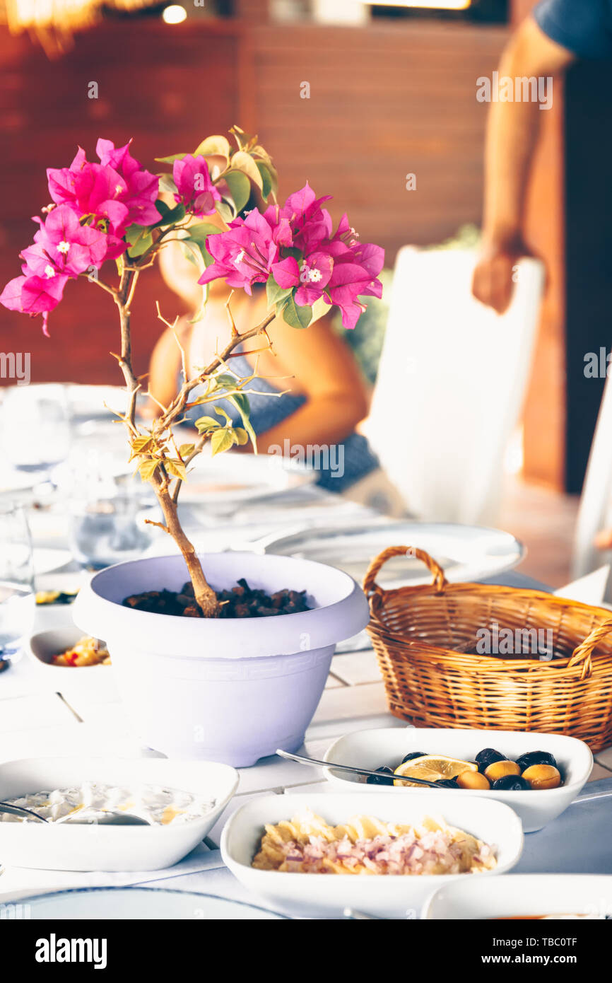 Fucsia flower in a pot and meze starters in an outdoor greek restaurant ...