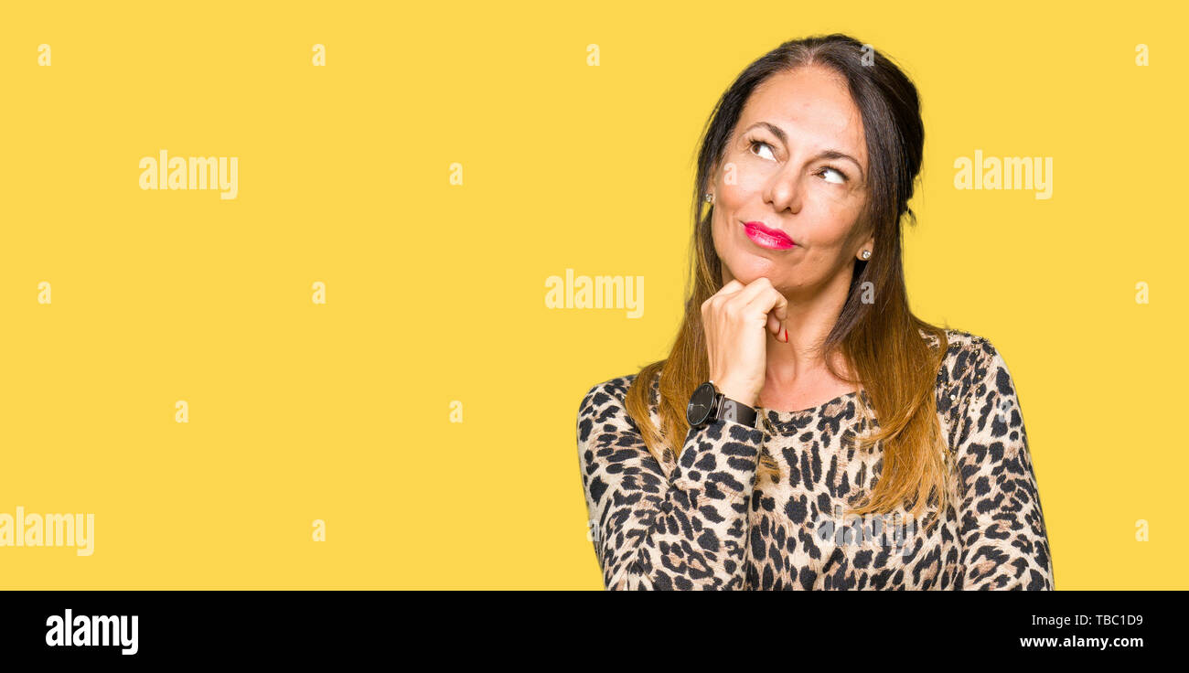 Beautiful middle age woman wearing leopard animal print dress with hand on chin thinking about ...