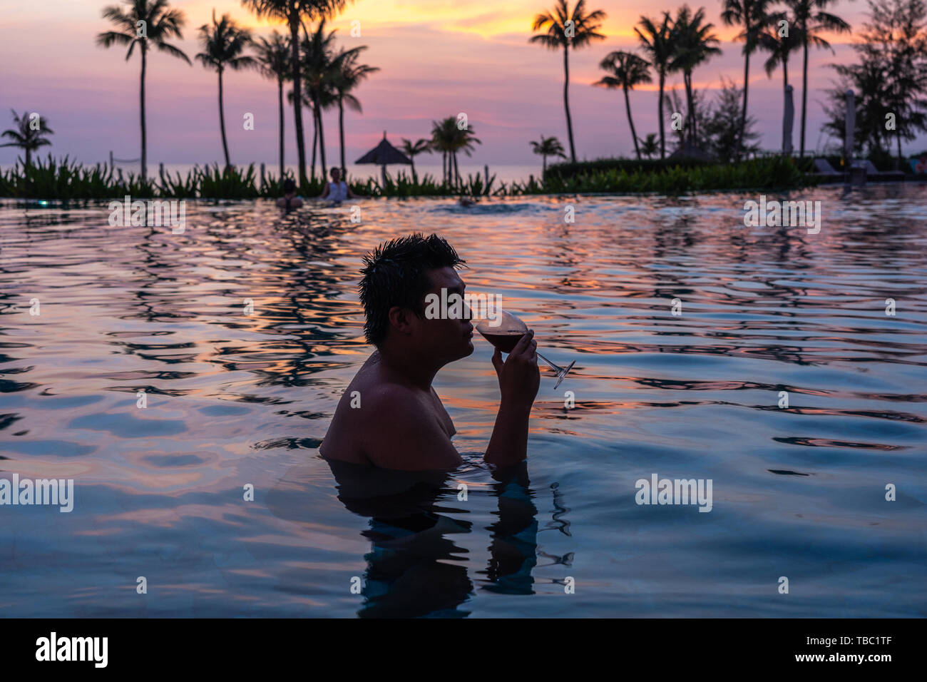 Asian man drinking red wine in the swimming pool Stock Photo - Alamy