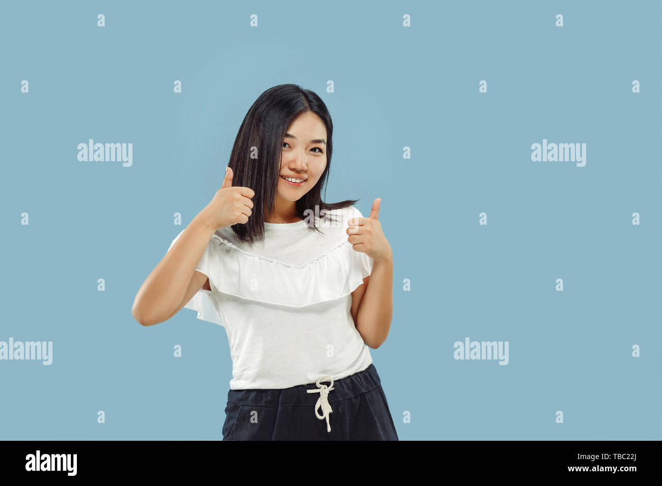 Korean young woman's half-length portrait on blue studio background ...