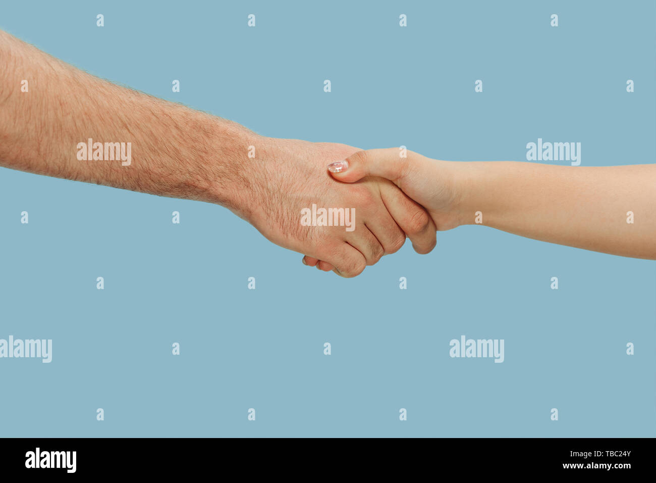Closeup shot of human holding hands isolated on blue studio background ...