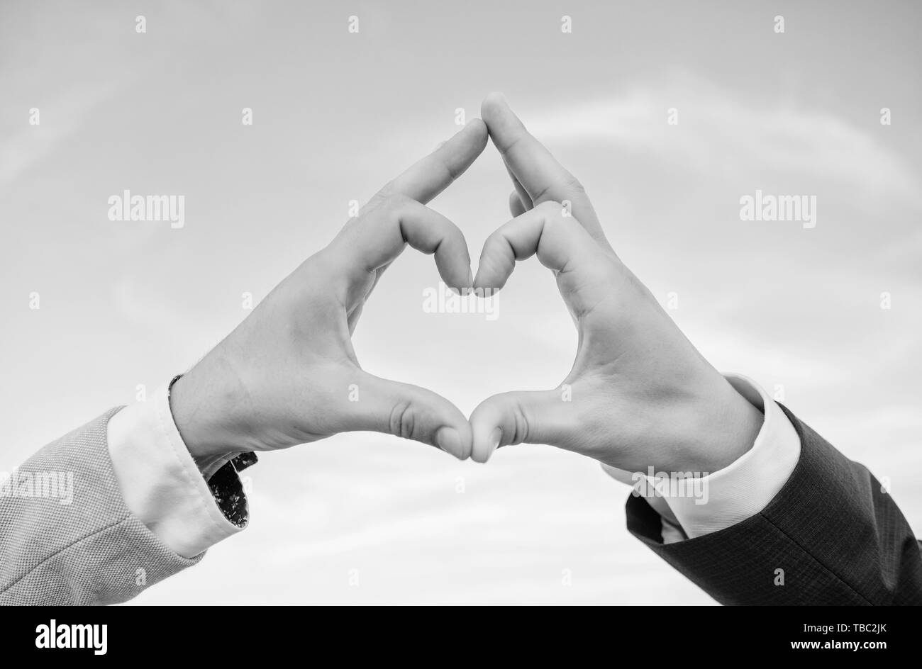 Hands put together in heart shape blue sky background. Love symbol ...