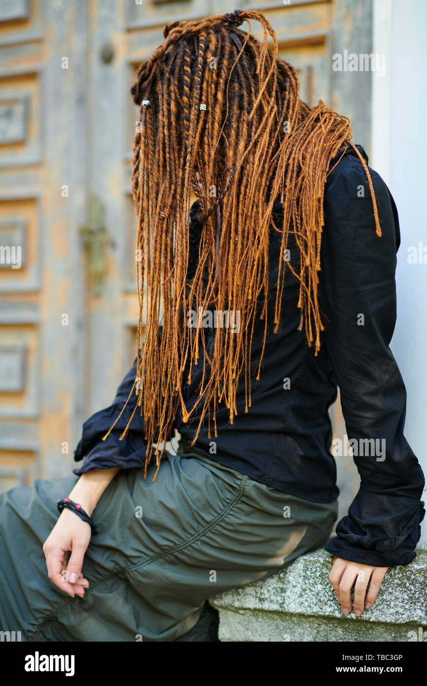 dreadlocks fashionable girl posing at old wooden door background. side ...