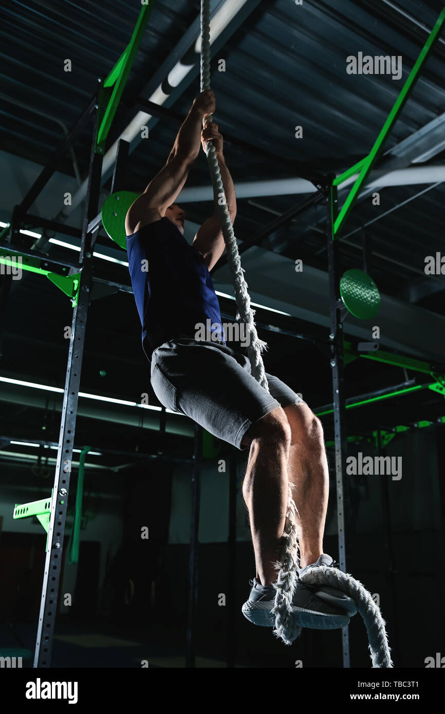 Young sporty man climbing up the rope in gym Stock Photo - Alamy
