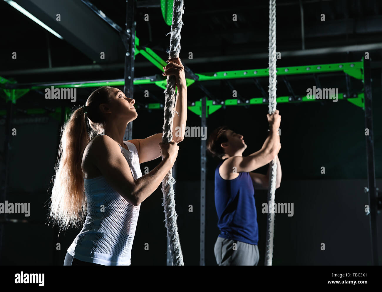 Young sporty couple is going to climb up the rope in gym Stock Photo ...