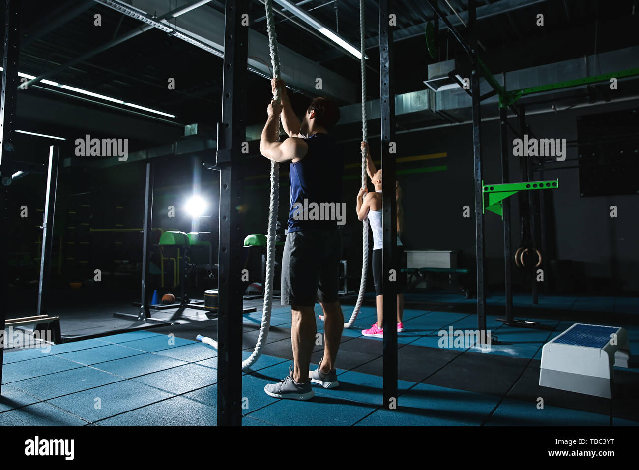 Young sporty couple is going to climb up the rope in gym Stock Photo ...