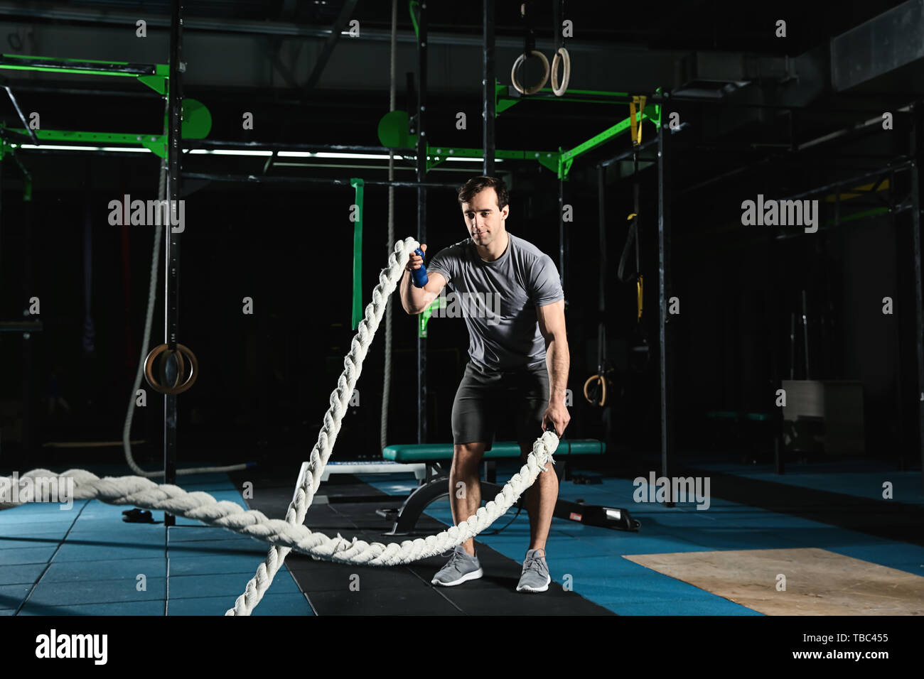 Young sporty man doing battle rope exercise in gym Stock Photo - Alamy