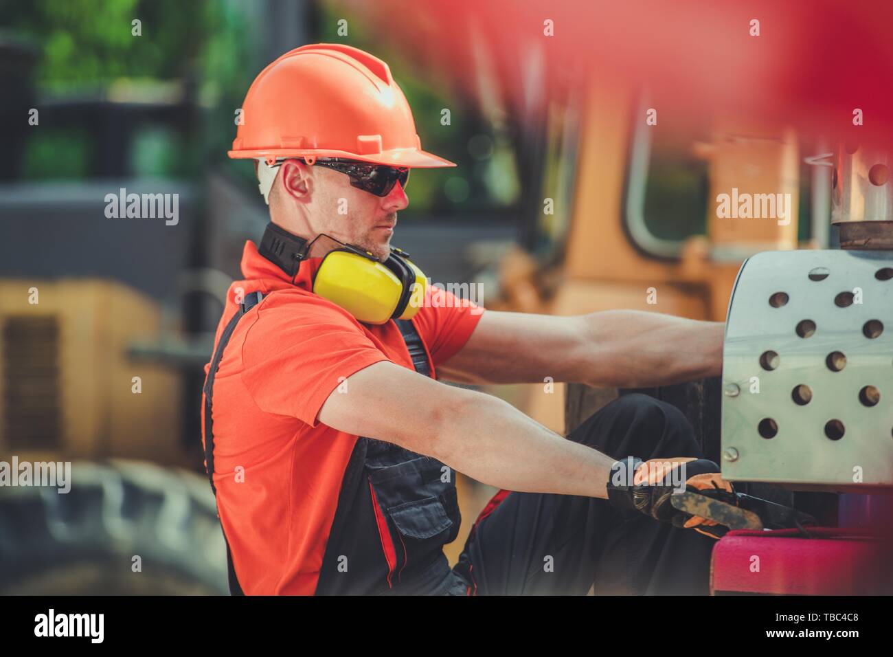 Heavy Construction Equipment Worker Between Machines. Caucasian Men in ...