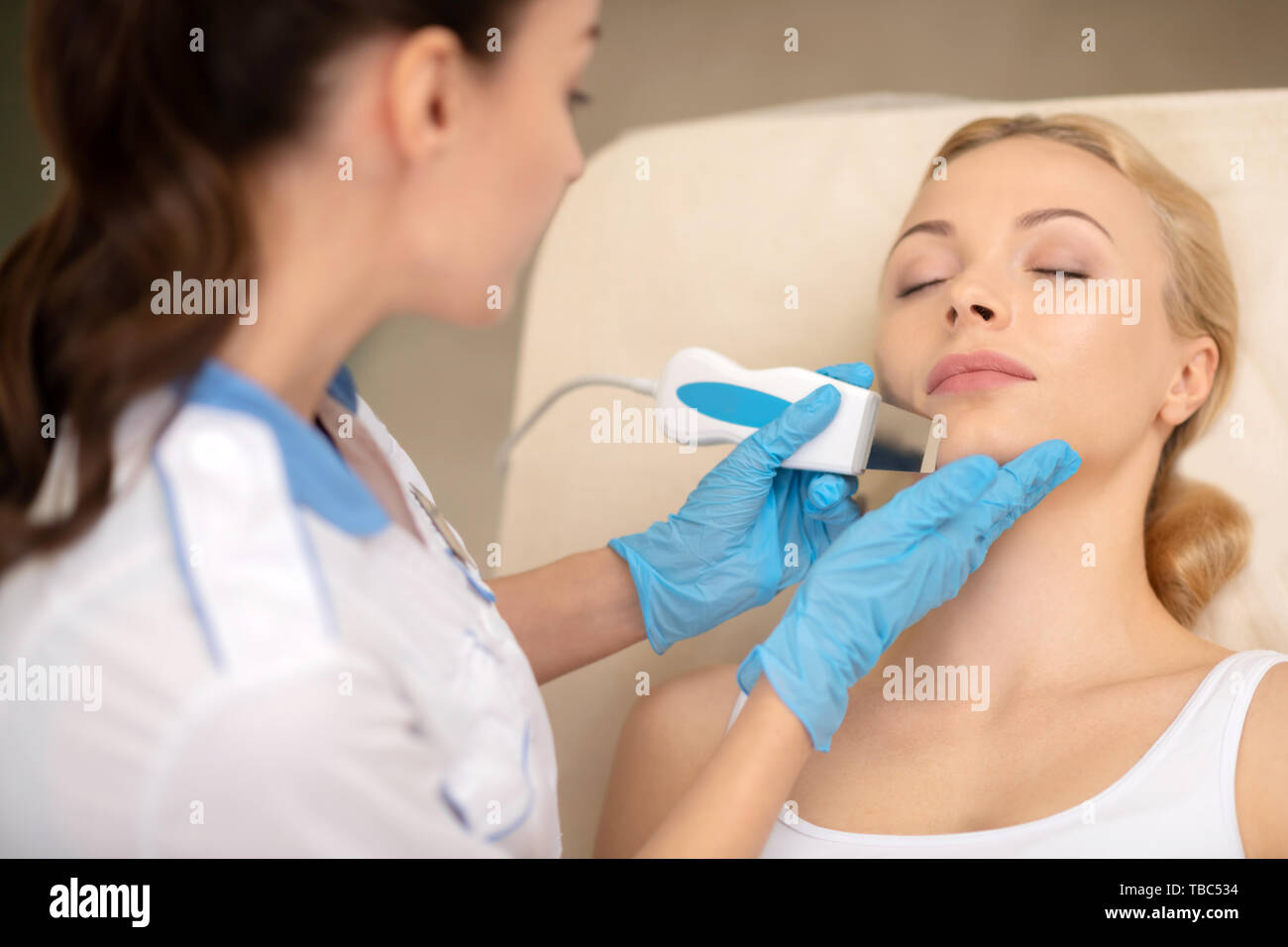 Skin on chin. Dark-haired professional dermatologist cleansing skin on ...