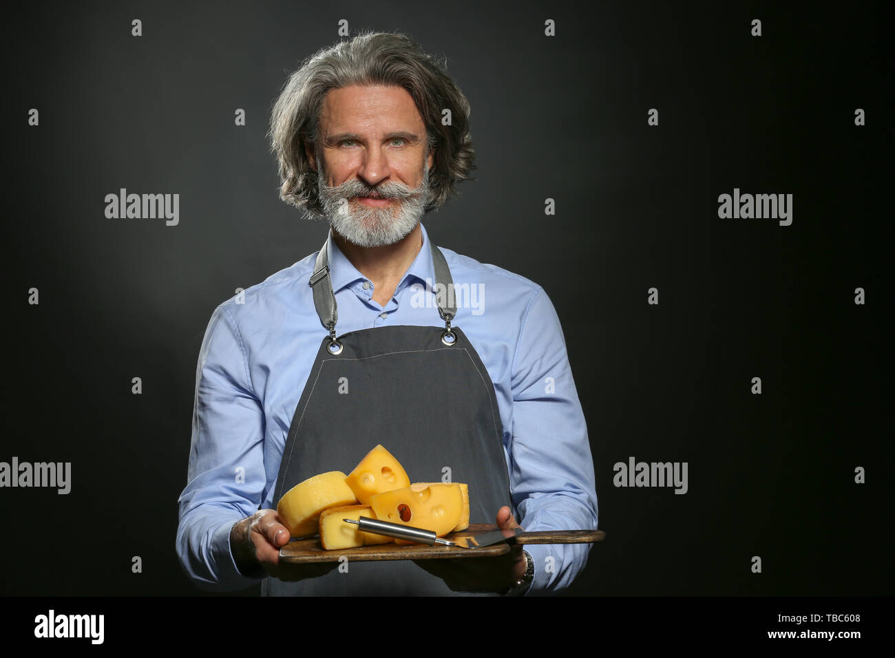 Male owner of cheese store on dark background Stock Photo - Alamy