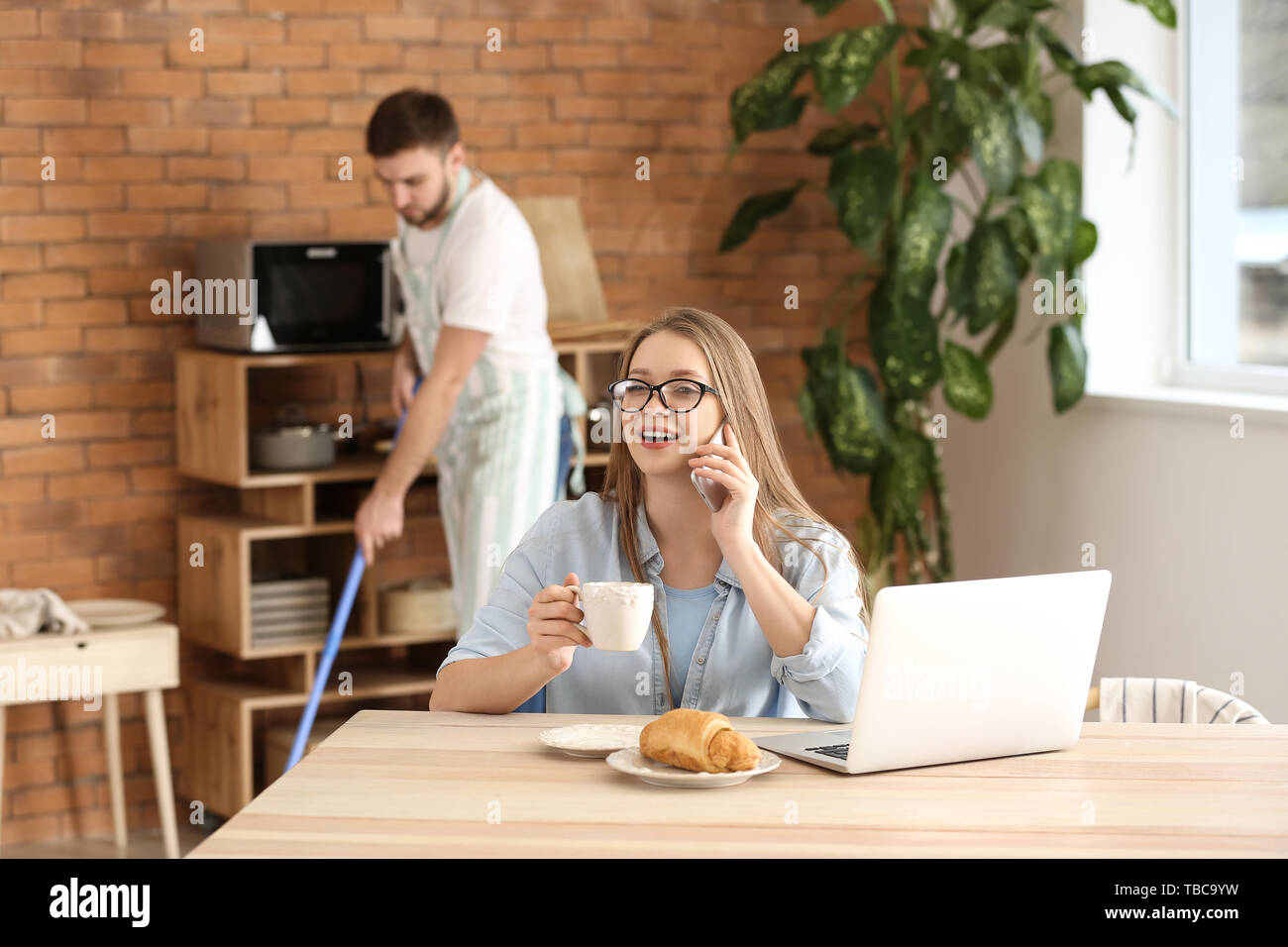 Busy wife working while her husband doing chores at home Stock Photo ...