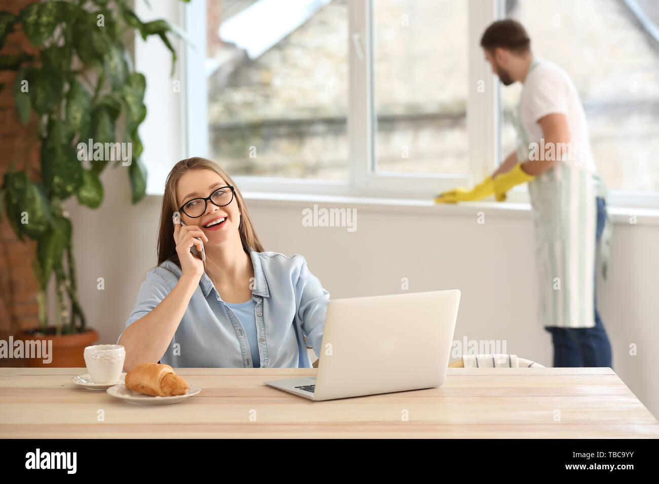 Busy wife working while her husband doing chores at home Stock Photo ...