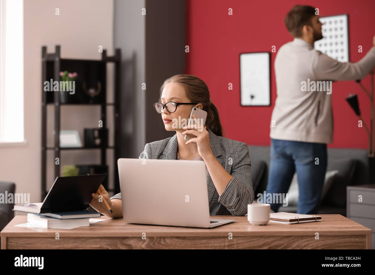 Busy wife working at table while her husband doing chores at home Stock ...
