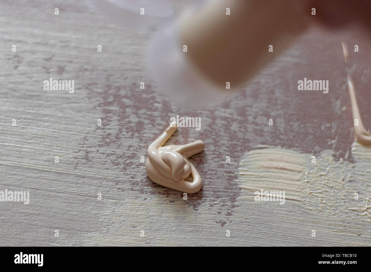 light yellow acrylic paint being squeezed out of the tube on a surface ...