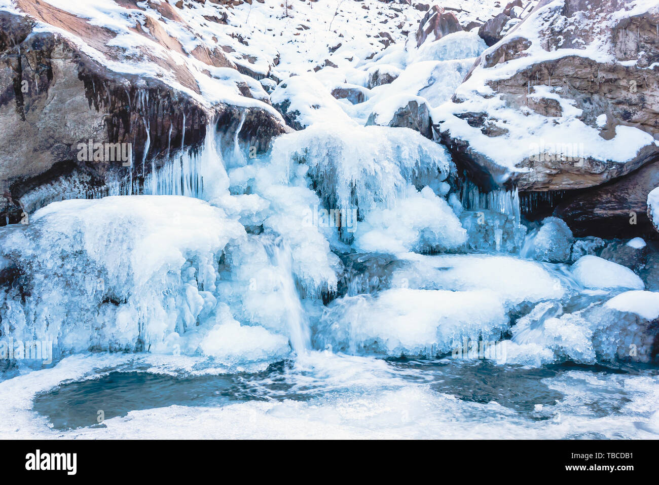 Winter mountain river under ice. Water froze and turned into icicles ...