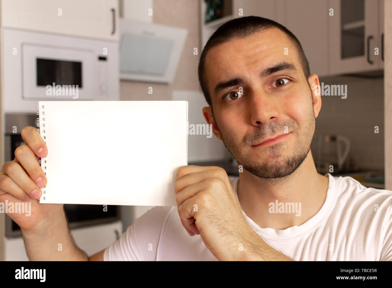 Young man holding and show blank paper notepad with space for text ...