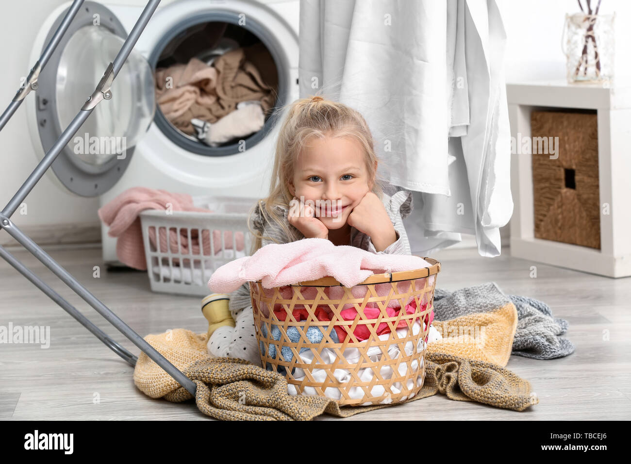 Cute little girl at home on laundry day Stock Photo - Alamy
