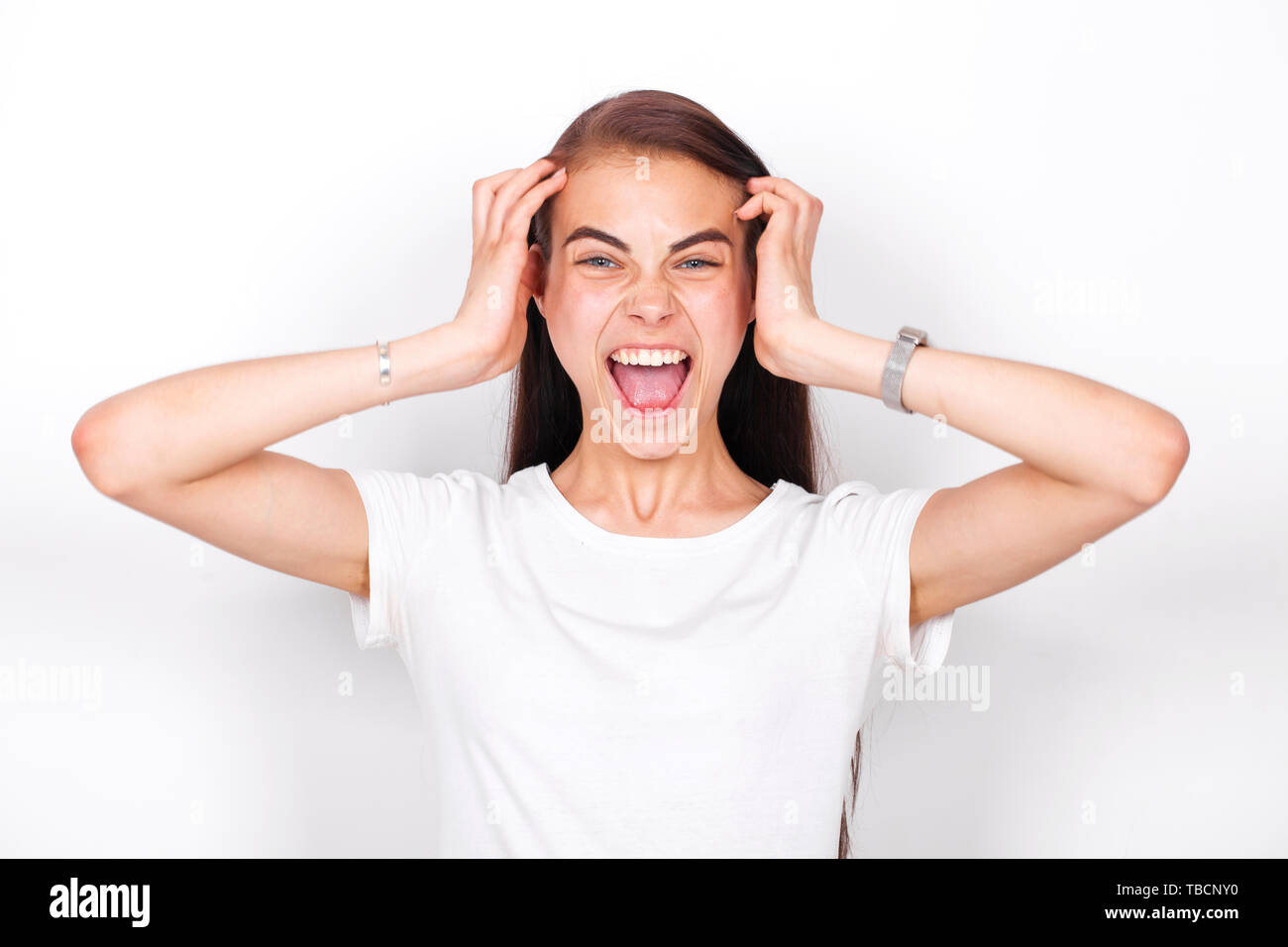 Young beautiful girl screaming in the studio on a white background ...
