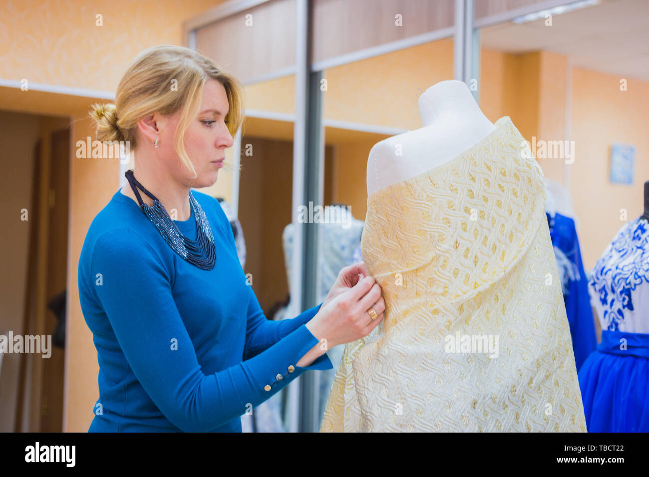 Fashion designer working with new model tailoring dress on mannequin ...