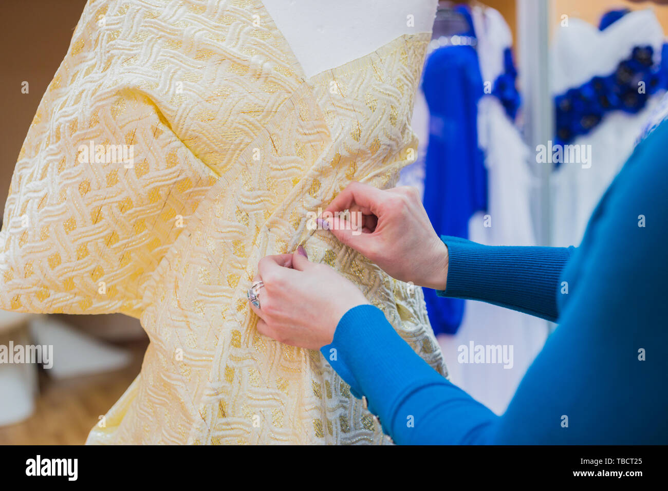 Fashion designer working with new model tailoring dress on mannequin ...