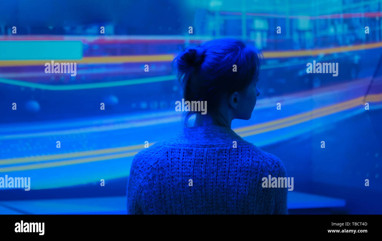 Woman looking around and watching video presentation on large display ...