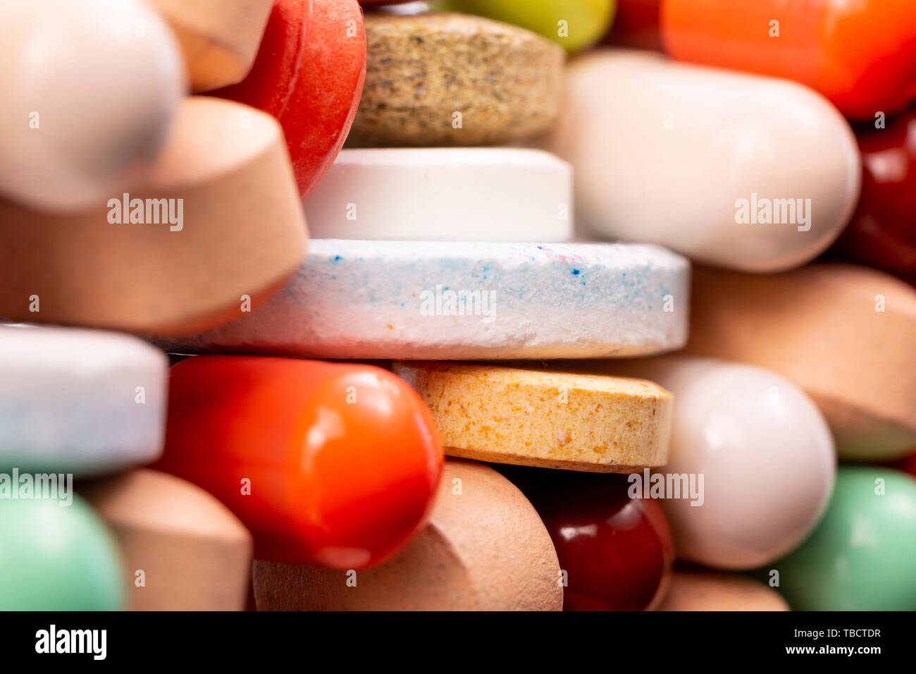 Different colorful pills and capsules stacked. Global pharmaceutical ...