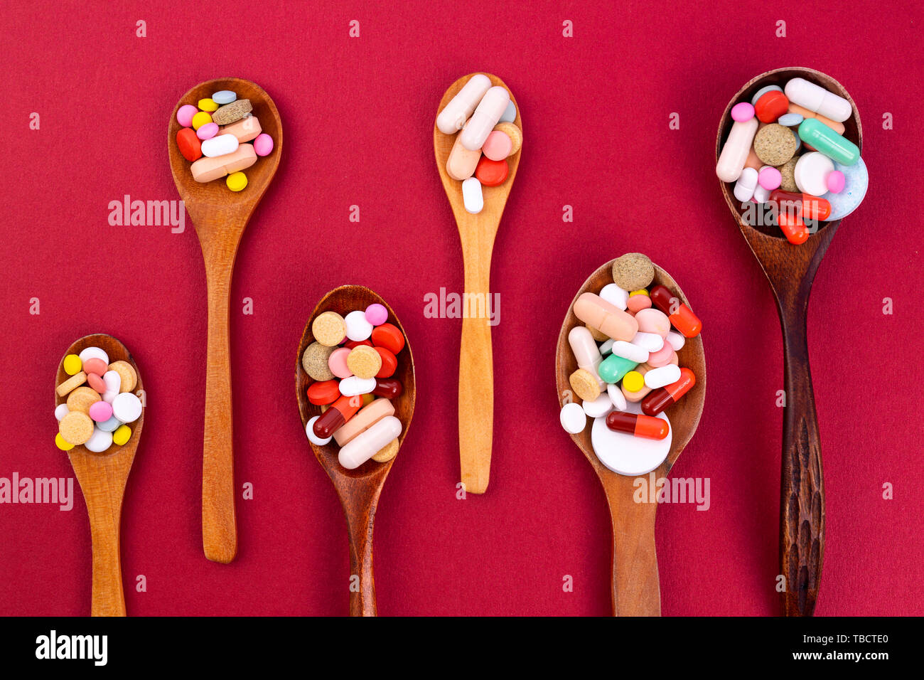 Different colorful pills and capsules in wooden spoons. Global ...