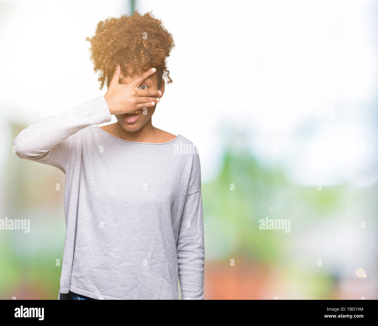 Beautiful young african american woman over isolated background peeking ...