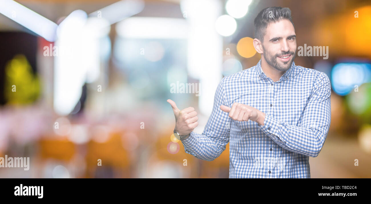 Young handsome man over isolated background Pointing to the back behind ...