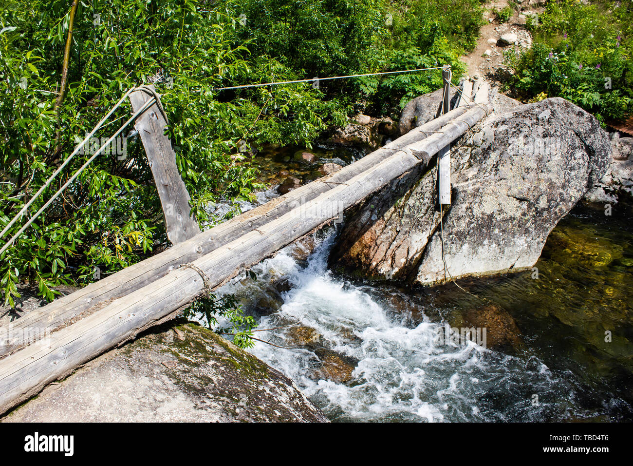 Old wooden tourist bridge made of woods and ropes across mountain river ...